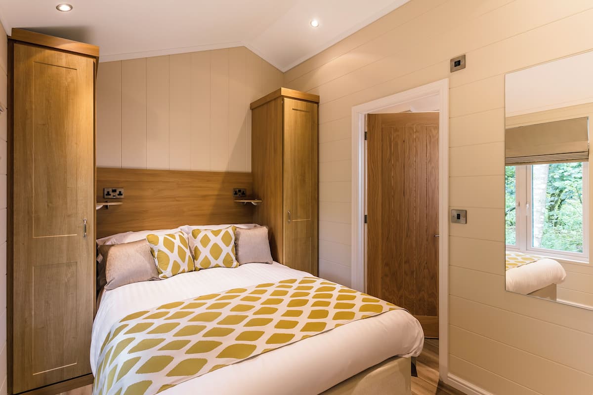 Quarto com cama, guarda-roupa de madeira e espelho.
