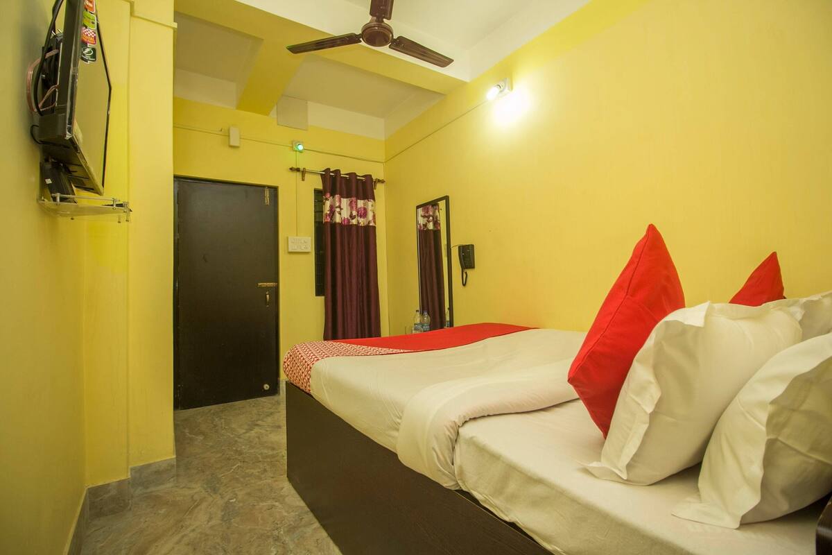 Quarto de hotel com cama, ventoinha no teto, porta e espelho.