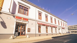 Um edifício de dois andares com uma placa indicando 'Forum Hotel & Restaurant' e uma fachada visível com um quadro de menu.