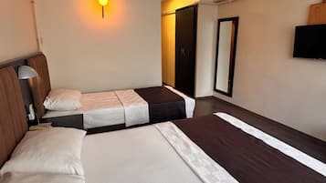 Quarto de hotel com duas camas, uma televisão de tela plana, um espelho e um ar-condicionado fixado na parede.