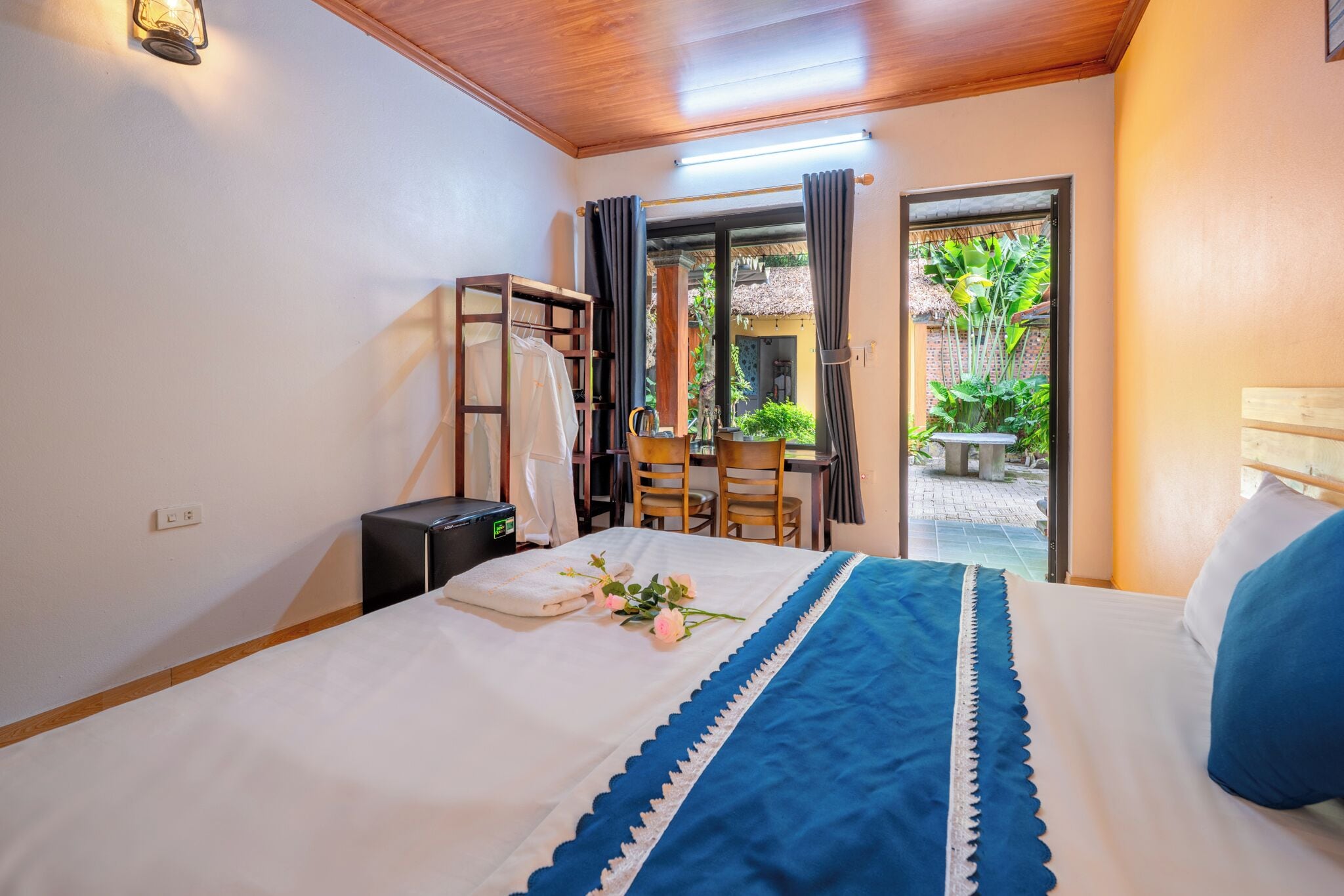 Quarto de hotel com cama, secretária e cadeira, guarda-roupa e vista para o exterior.