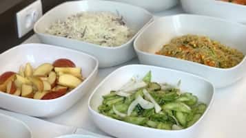 Uma mesa de buffet com diversos alimentos em tigelas brancas.