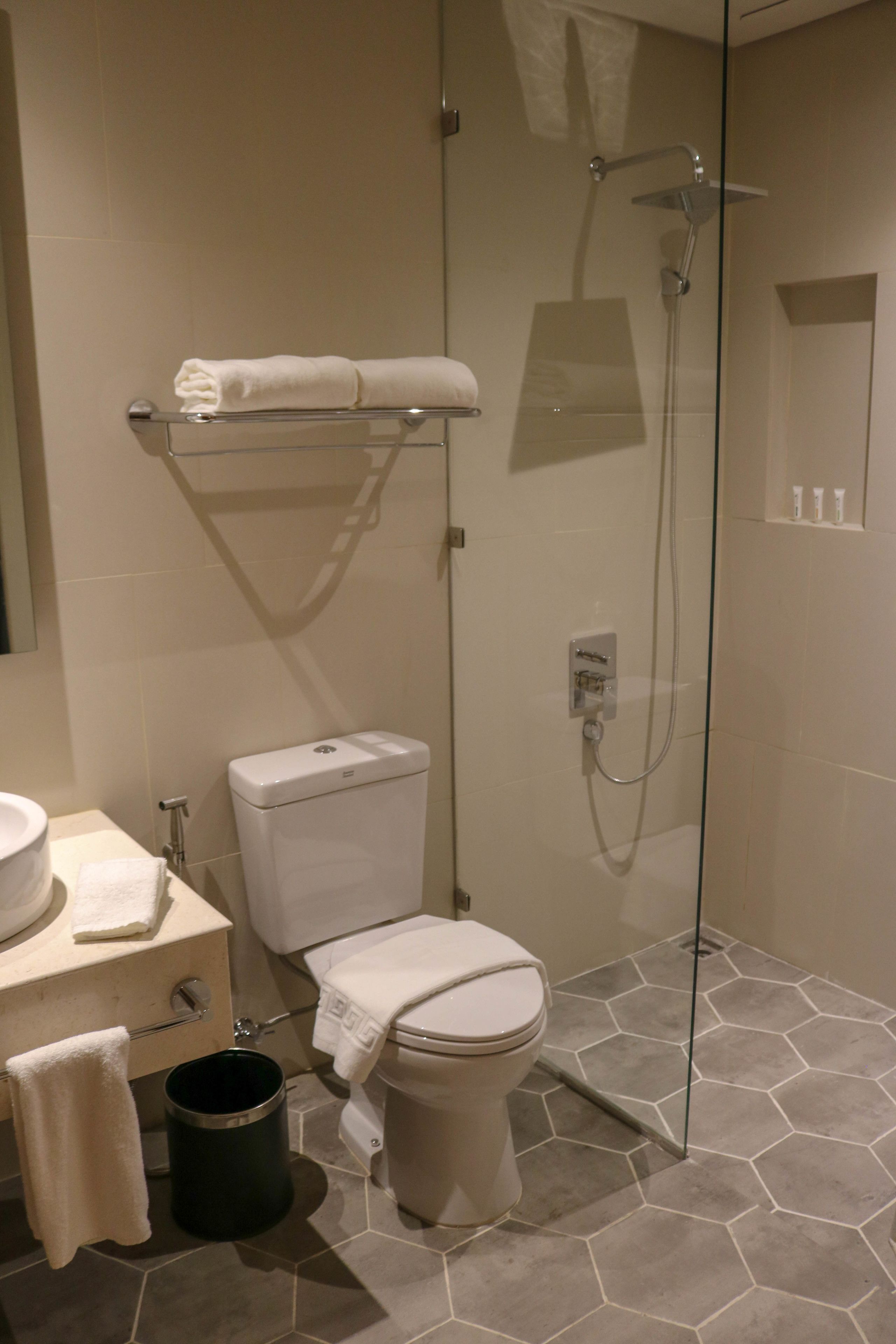 Um banheiro moderno com chuveiro envidraçado, vaso sanitário, pia e porta-toalhas.
