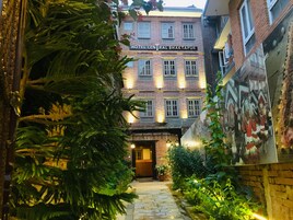 Entrada de um hotel com fachada de tijolos, várias janelas e uma placa com a inscrição "HOTEL CENTRAL BHAKTAPUR".