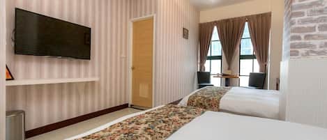 Quarto de hotel com duas camas, televisão fixada na parede, uma mesinha e uma janela com cortinas.
