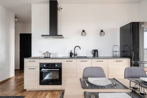 Cozinha moderna com forno embutido, exaustor preto e área de refeições com mesa posta para dois.