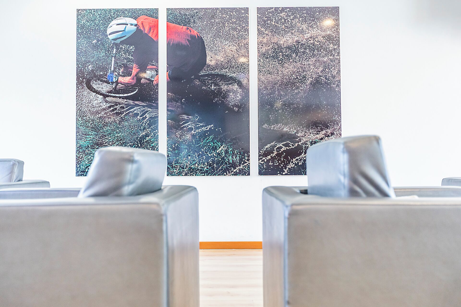 Quarto com uma grande obra de arte na parede retratando um ciclista. Há duas cadeiras em primeiro plano.