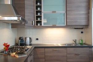 Uma cozinha moderna com fogão a gás, cafeteira e prateleira embutida com plantas em vasos.