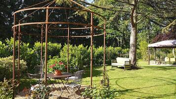 Um gazebo com mesa e cadeiras em um jardim.
