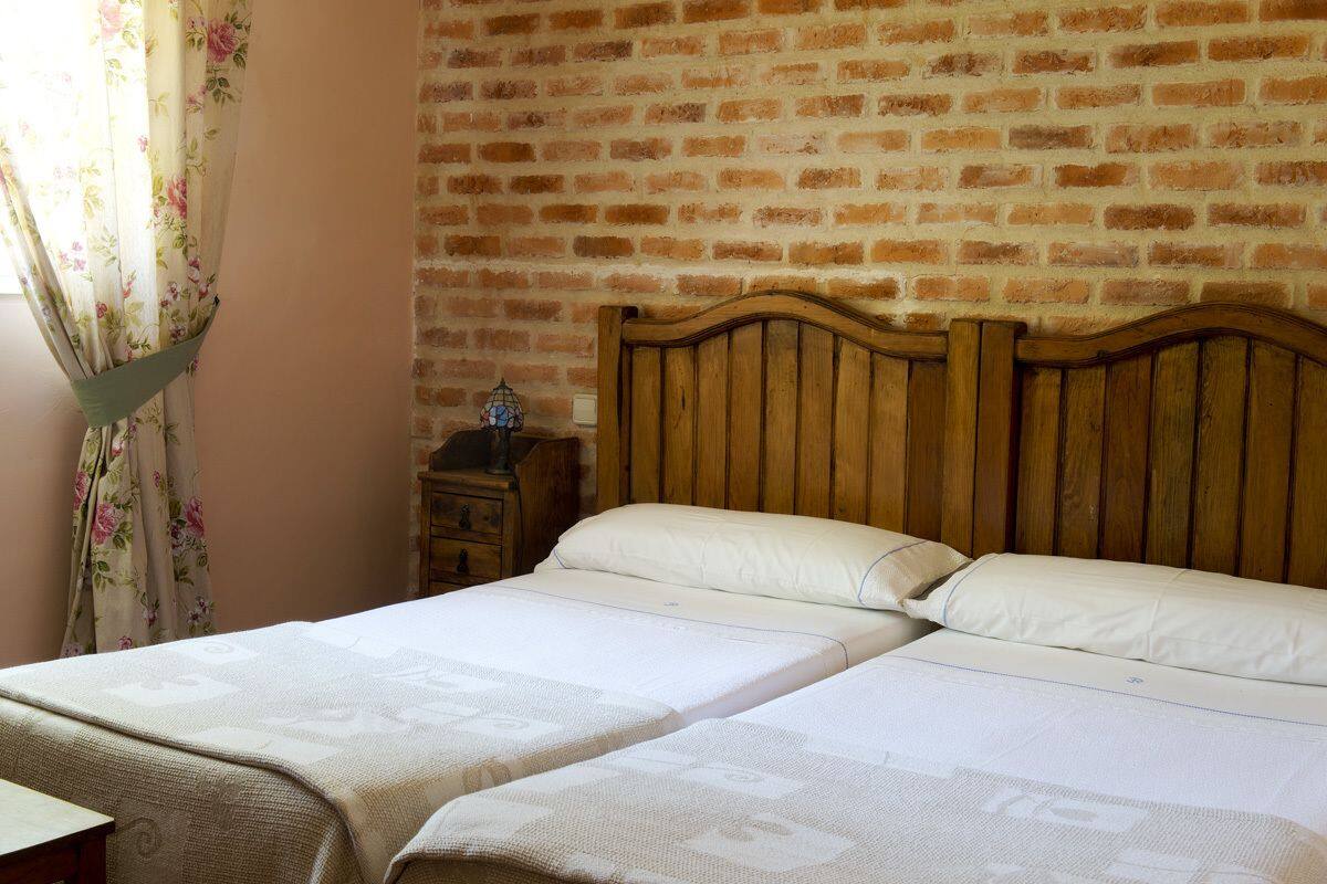 Uma cama de casal com cabeceira de madeira em um quarto com paredes de tijolo.