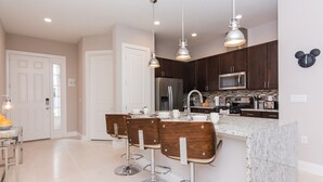 Uma cozinha moderna com armários de madeira escura, eletrodomésticos de aço inoxidável e uma ilha de mármore com banquetas.