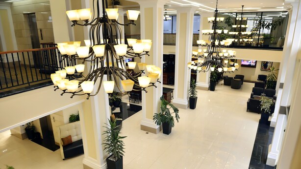Um hall amplo com várias luminárias, áreas de estar e plantas em vasos.