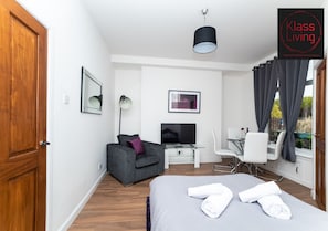 Quarto moderno com cama, televisão, escrivaninha e cadeira.
