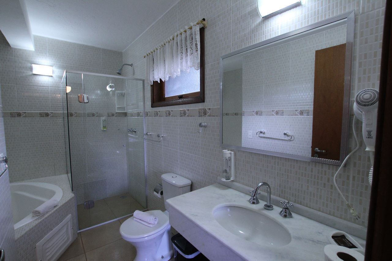 Casa de banho com cabine de duche em vidro, uma sanita branca e um espelho grande.