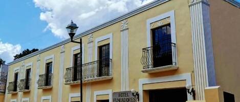 Um hotel com fachada amarela, várias varandas e uma placa indicando que é um hotel.