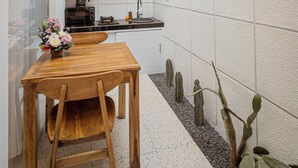 Uma cozinha moderna com azulejos brancos, uma mesa de jantar de madeira e diversas plantas.