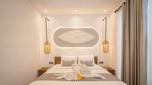 Quarto de hotel moderno com uma cama bem arrumada, um painel decorativo e duas luminárias fixadas na parede.