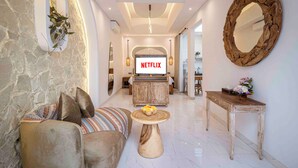 Uma sala de estar moderna com parede de destaque em pedra, mesa de centro de madeira e uma televisão exibindo 'NETFLIX'.