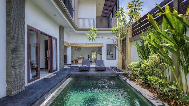 Uma casa moderna com piscina, varanda e vegetação exuberante.