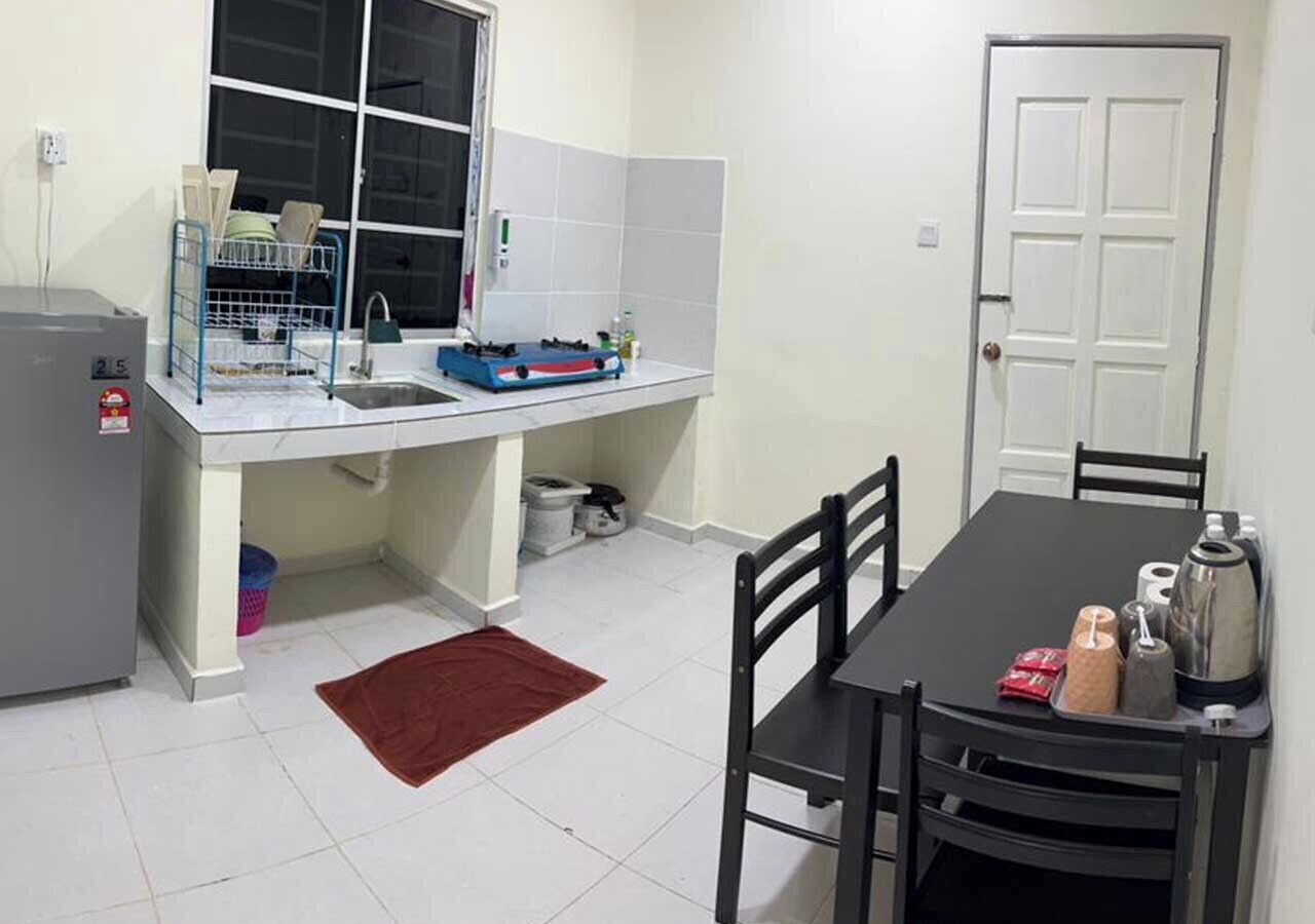 Cozinha compacta com geladeira, pia e área de refeições com cadeiras e mesa.