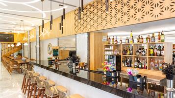 Uma área de bar moderna com um balcão extenso, banquetas e uma variedade de garrafas de bebidas.