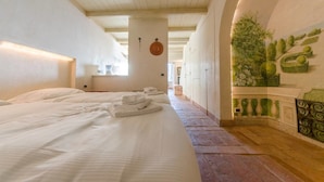 Quarto de hotel com duas camas, corredor e parede decorativa com vegetação.