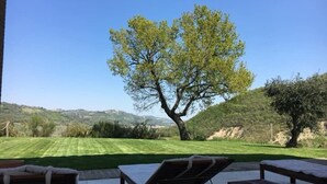 Um pátio com cadeiras de descanso e vista para uma paisagem gramada e colinas.