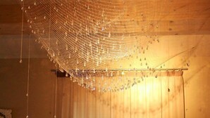 Quarto com teto de madeira, luminária pendente e cortinas leves.