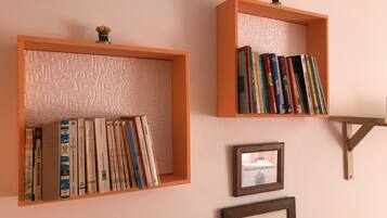 Duas estantes de madeira encostadas a uma parede, cada uma com livros e um pequeno objeto decorativo.