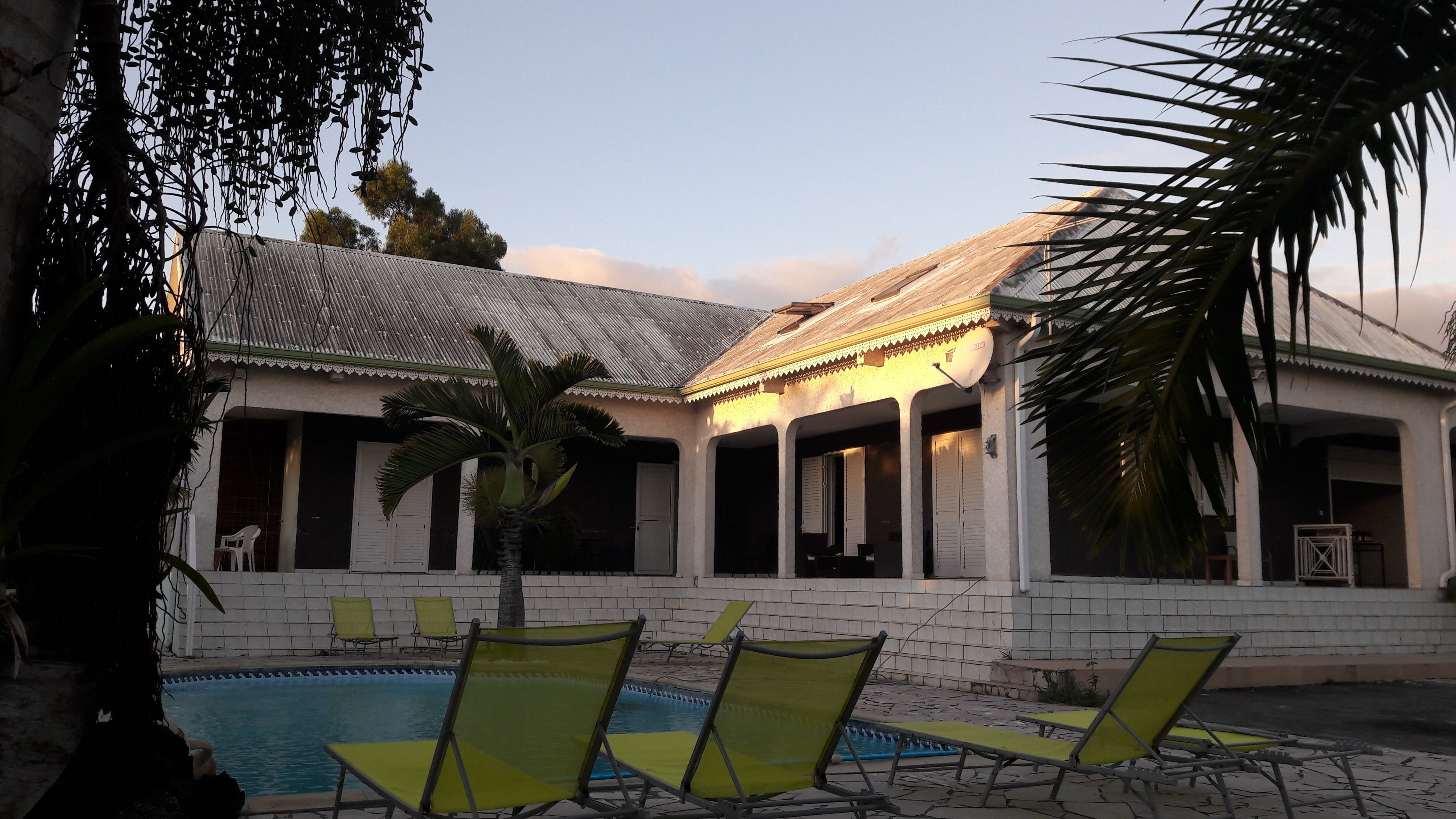 Um edifício com piscina, área de estar externa e um terraço coberto.