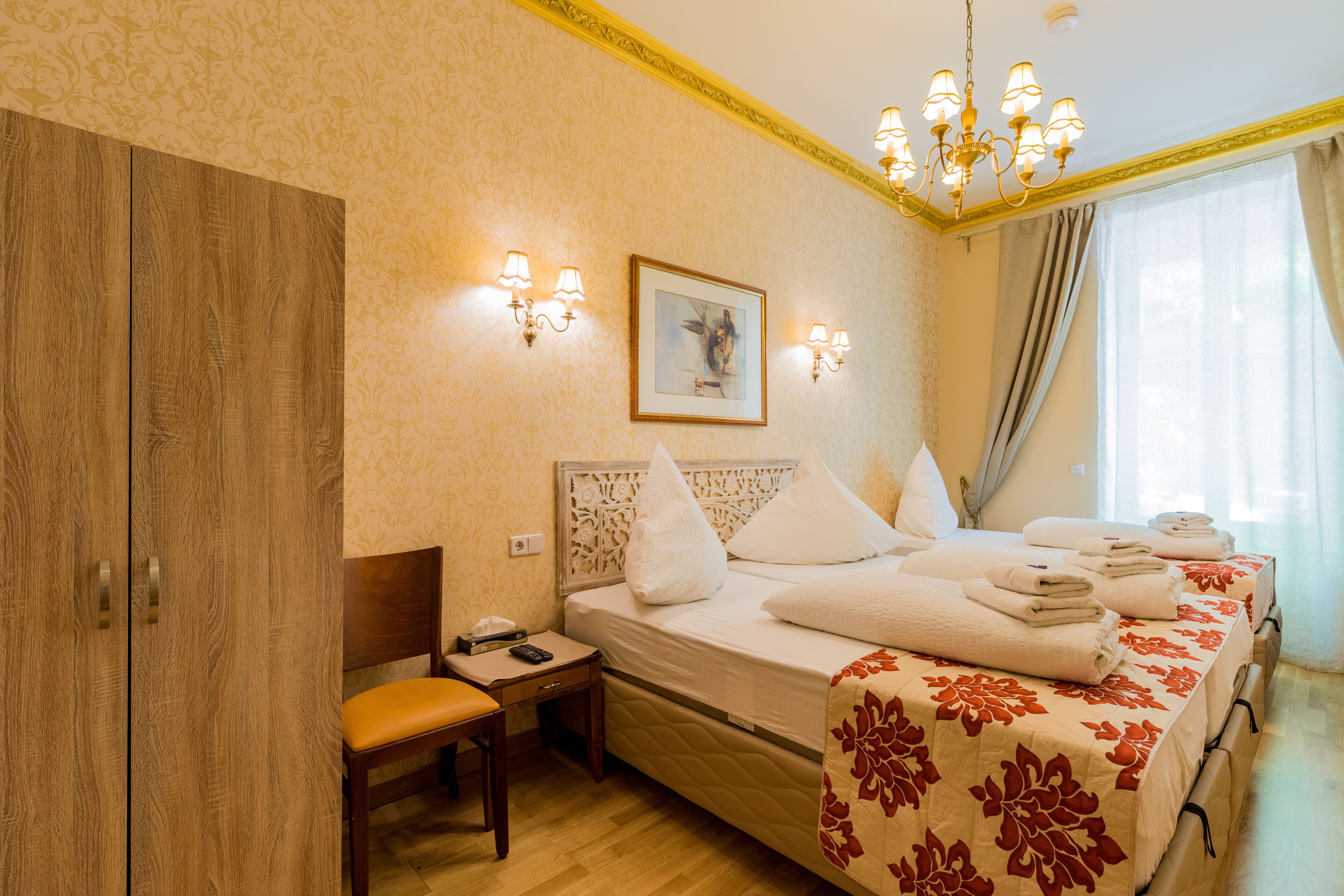 Quarto de hotel com cama, cadeira, mesa de cabeceira e guarda-roupa.