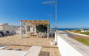 Terraço no telhado com área de estar ao ar livre, pérgola e vista para o mar.