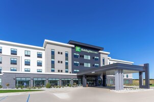 Um edifício de hotel moderno com uma placa visível para Holiday Inn & Suites.