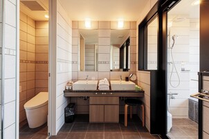 Uma casa de banho moderna com duas lavatórios, sanita e chuveiro.