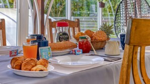 Disposição para o pequeno-almoço com croissants, pão, sumo e uma máquina de café Nescafe Classic.