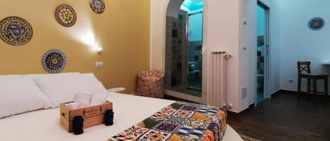 Quarto de hotel com cama, cômoda, espelho e porta para um banheiro.