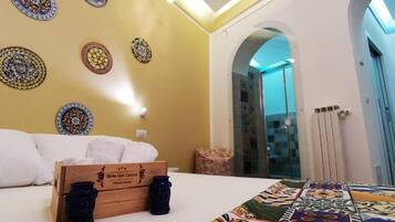 Quarto de hotel com uma cama, um caixote de madeira e uma parede decorativa com azulejos estampados.