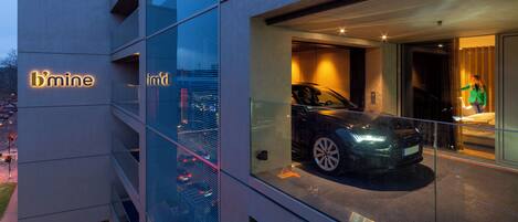 Um edifício moderno com fachada de vidro, um carro exposto na vitrine e a placa 'b'mine'.