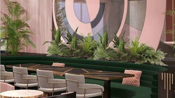 Um interior moderno com área de estar verde, mesas e cadeiras.