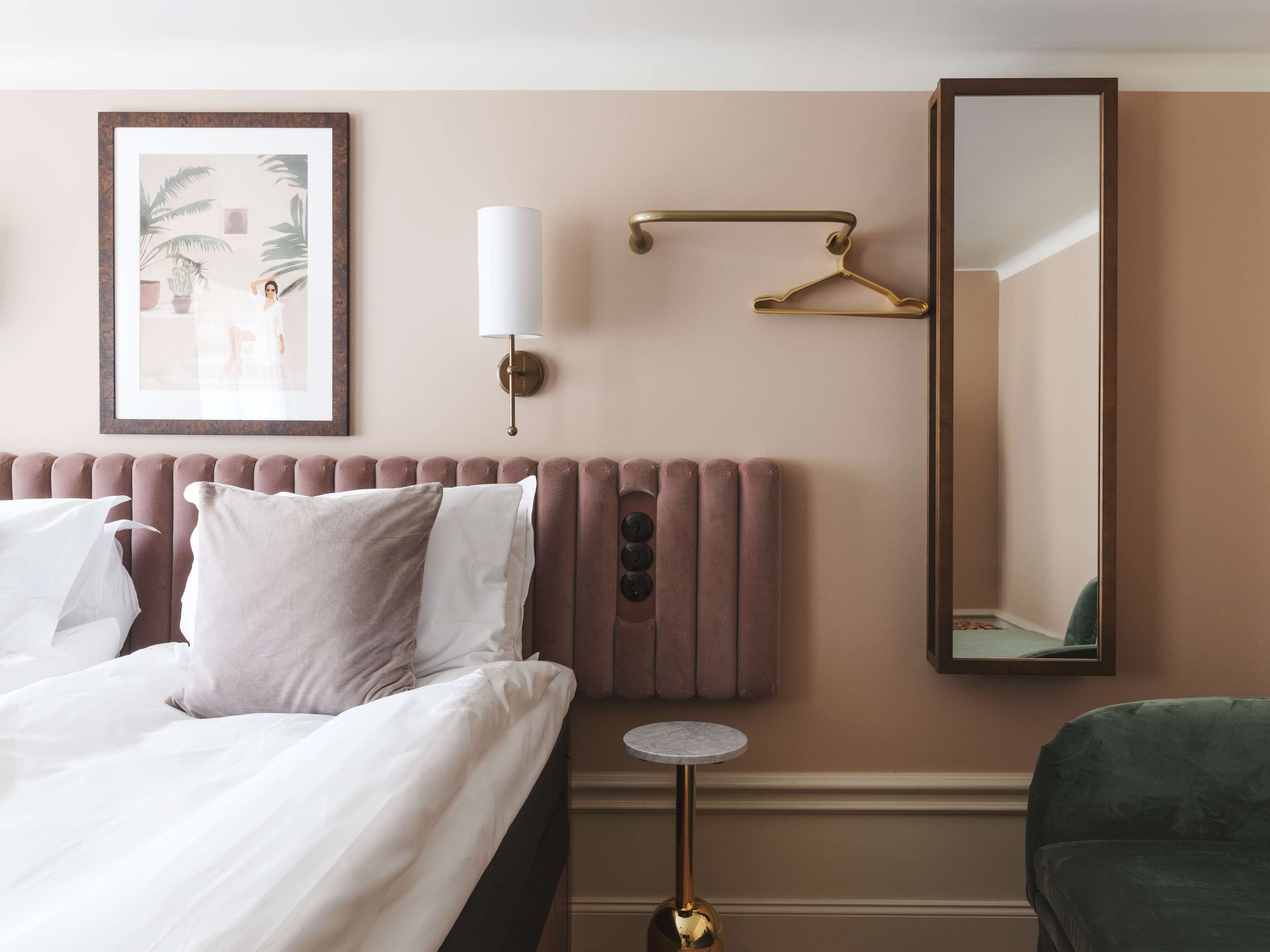 Quarto de hotel com cama, mesa de cabeceira, luminária pendente, quadro na parede e espelho.