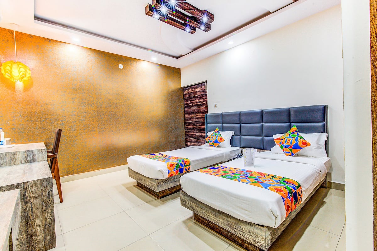 Quarto de hotel com duas camas, uma escrivaninha e uma cadeira.