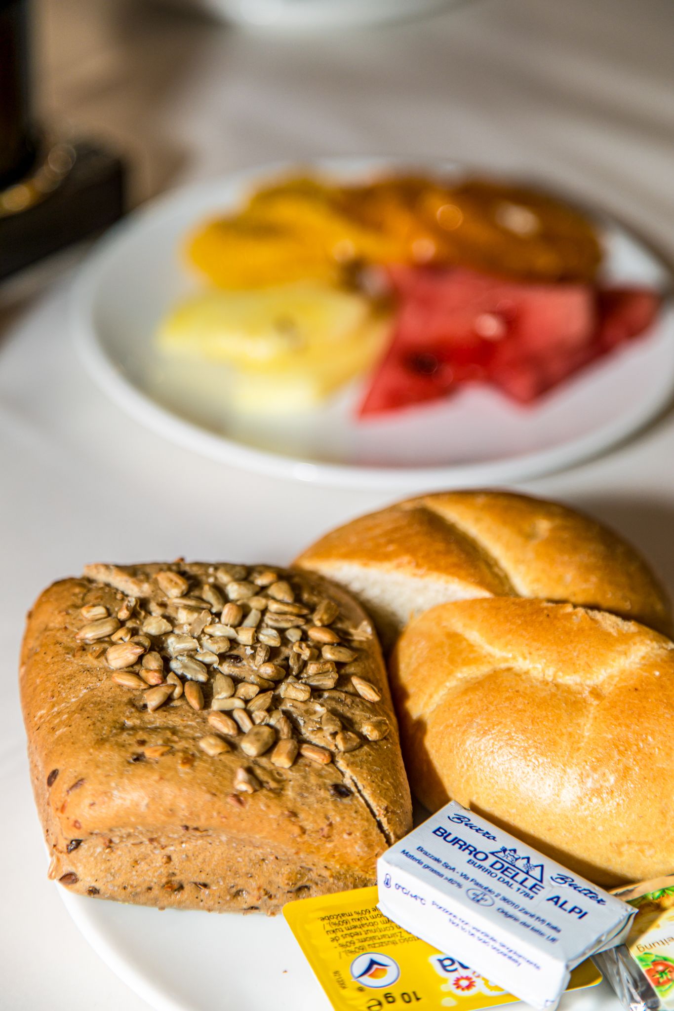 Um prato com pão, um pãozinho e fatias de fruta.