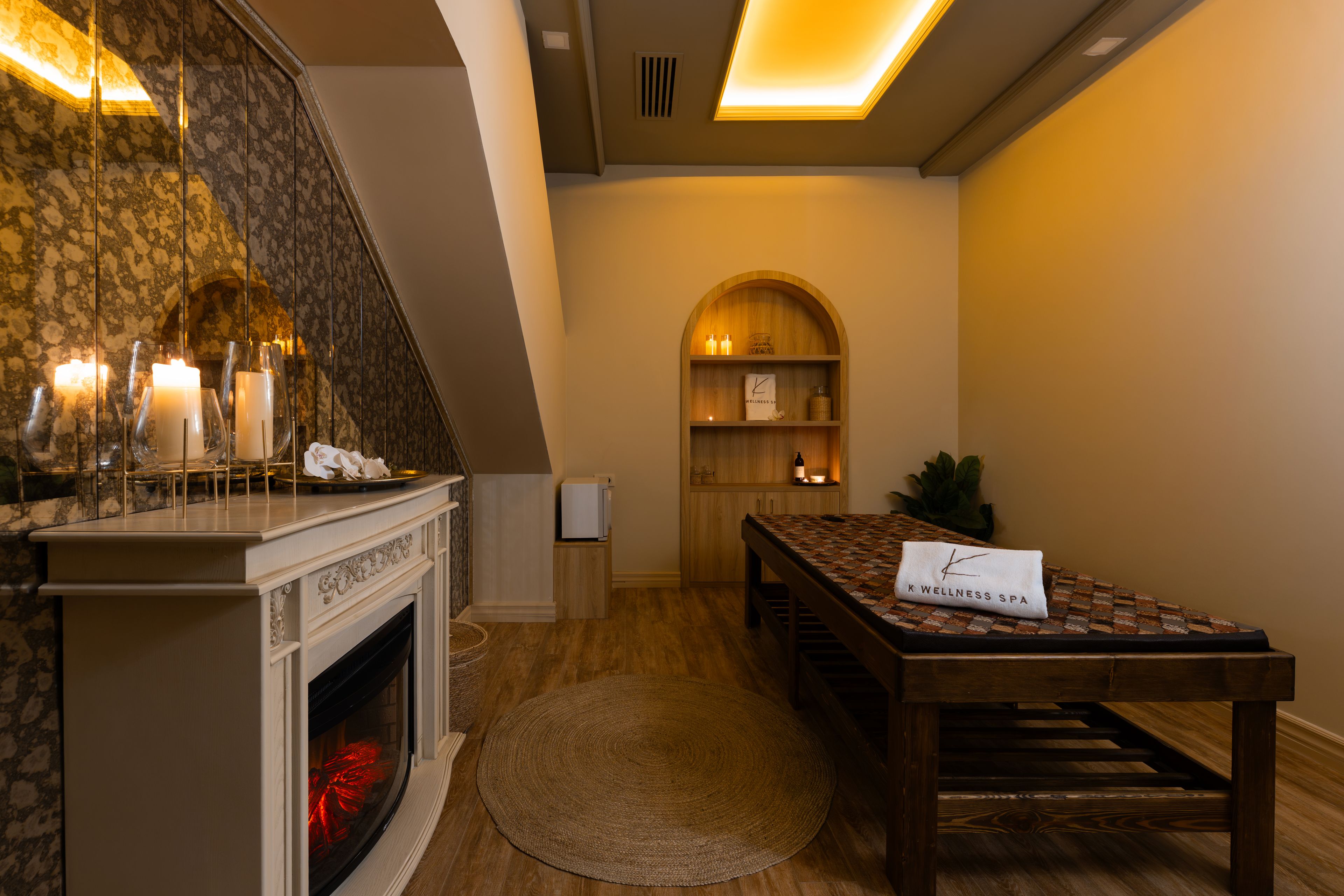 Quarto com lareira, mesa de jantar e prateleira de madeira com velas.