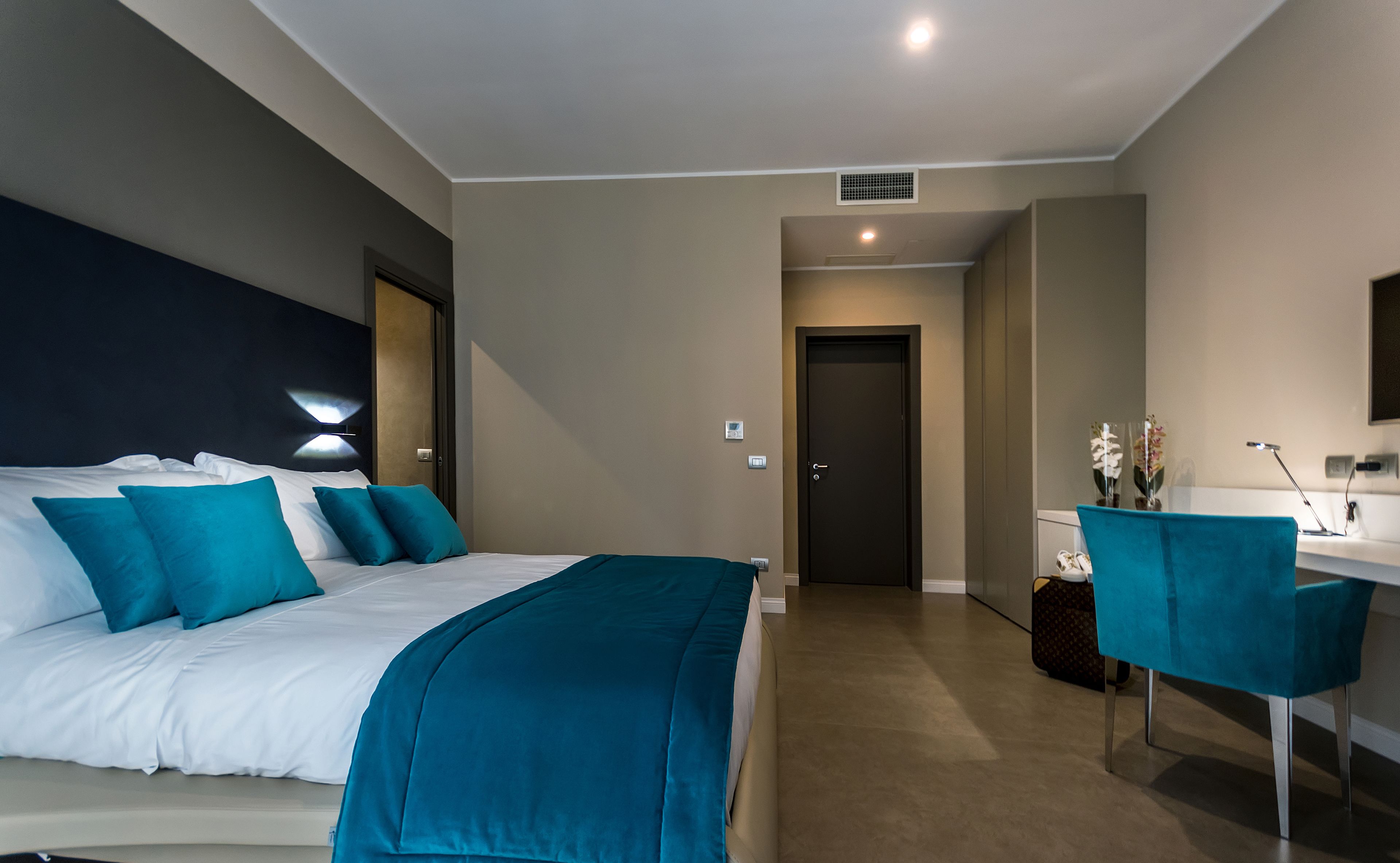 Quarto de hotel moderno com uma cama grande, uma mesa e um banheiro.