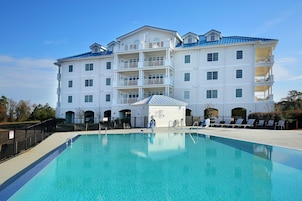 Um hotel grande, com vários andares e uma piscina na frente.