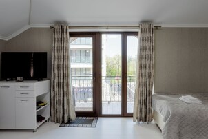 Quarto com cama, TV, guarda-roupa e varanda com grades.