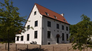 Um edifício branco com telhado de telhas vermelhas, várias janelas e fachada de pedra.