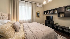 Quarto com cama grande, televisão e estantes embutidas.