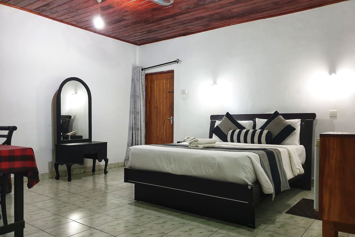 Quarto com cama, espelho, penteadeira e porta.