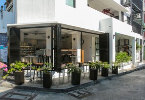 Um hotel moderno com área de estar externa, cozinha à vista e plantas em vasos.